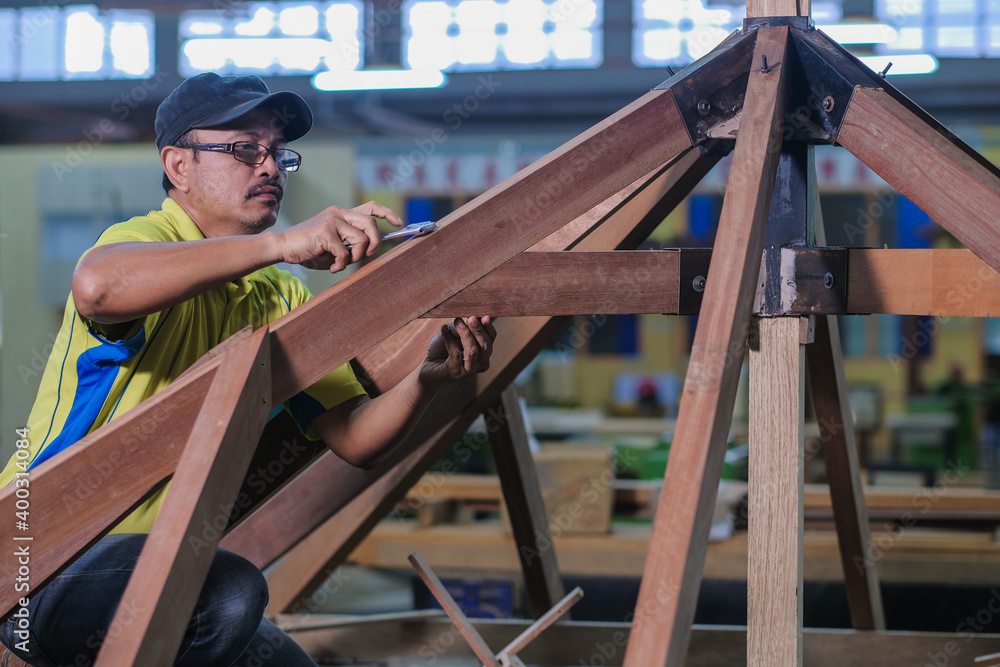 Carpenter using bolt and nut in installation of roof rafters on a new ...