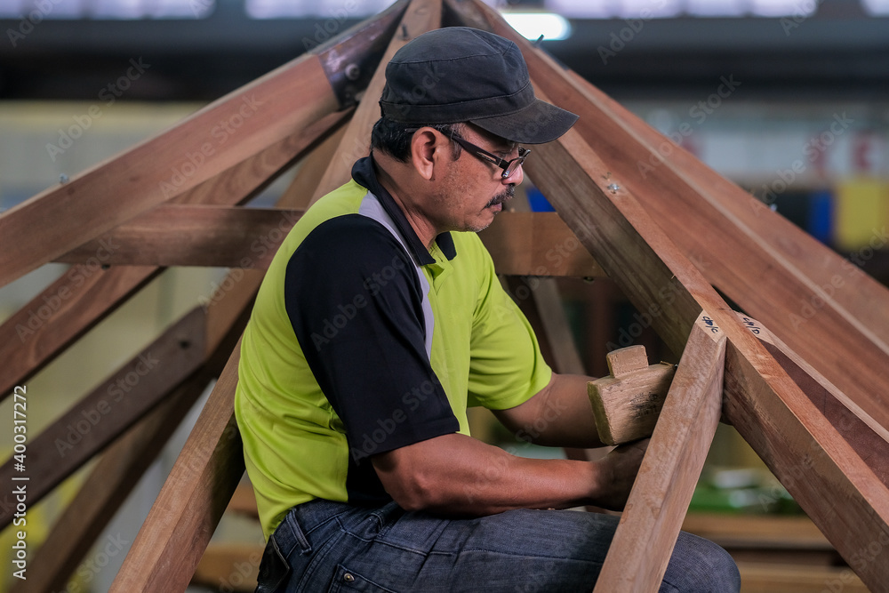 Carpenter using bolt and nut in installation of roof rafters on a new ...