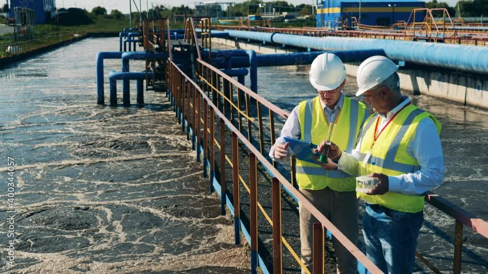 Wastewater operators checking water condition at a sewage treatment ...