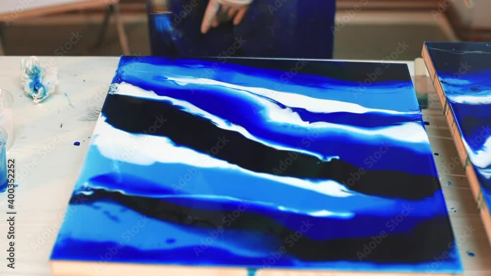 The artist's hand heats the surface of the painting with fire, making ...