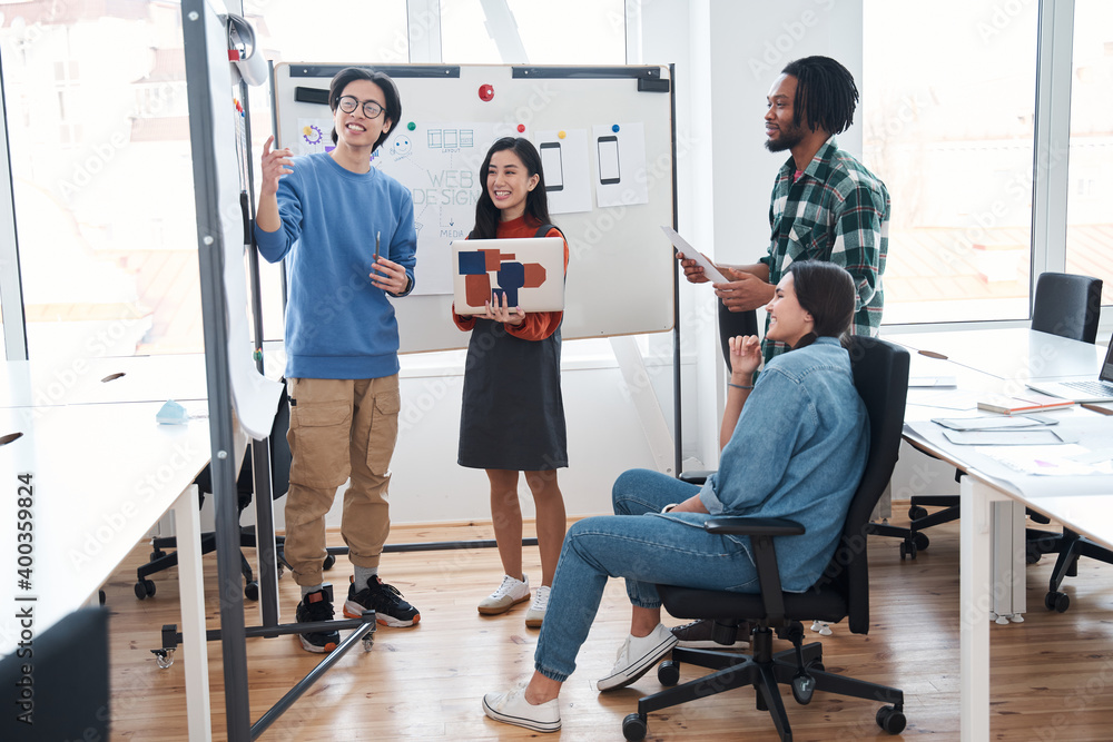 Smiling students standing at the classroom and discussing project on ...