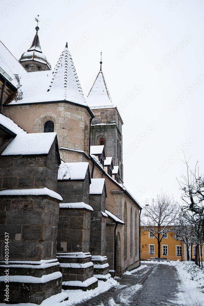Snow covered street with old stone church, lamppost and trees with a ...
