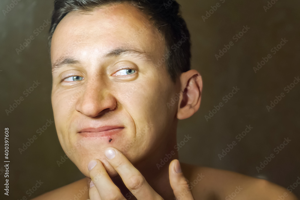 Man with grey eyes looks carefully at mirror reflection of face and ...