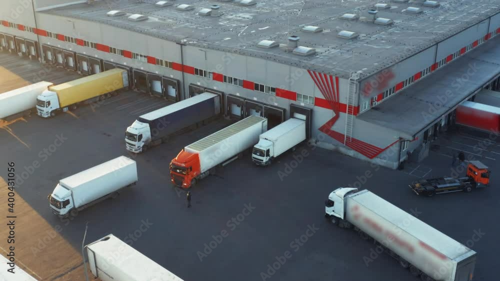 Trucks with semi-trailers stand at warehouse ramps in the logistics ...