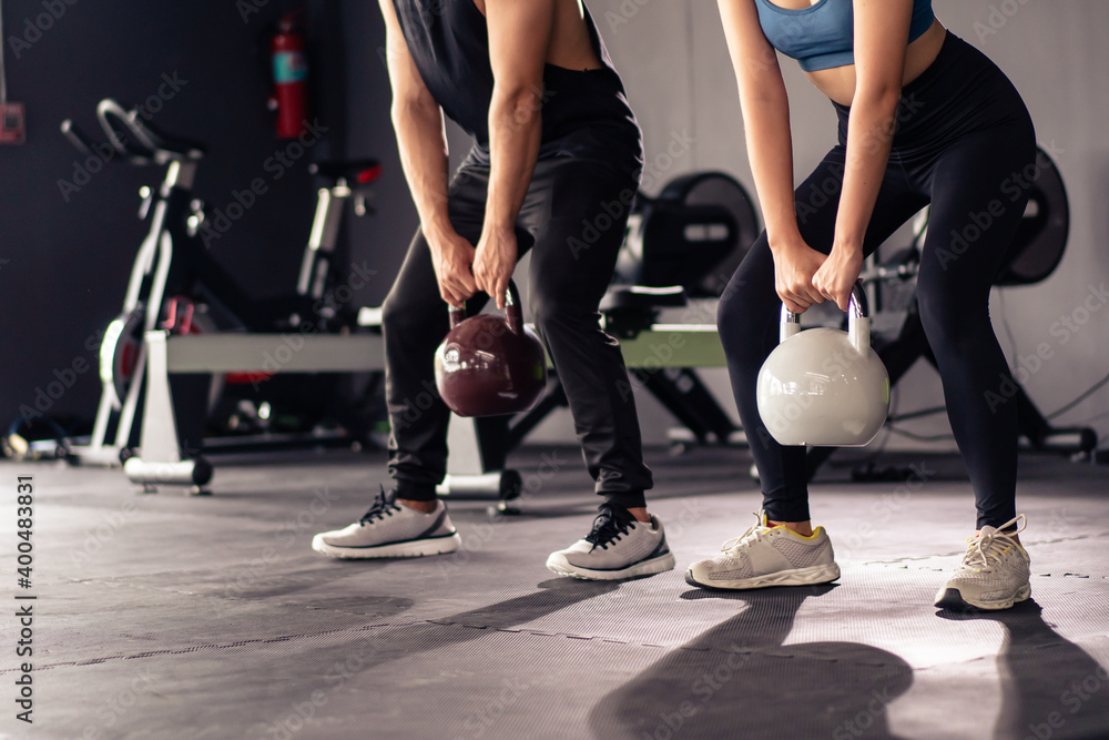Powerful sportive people lifting up a heavy kettle ball in a gym, body ...