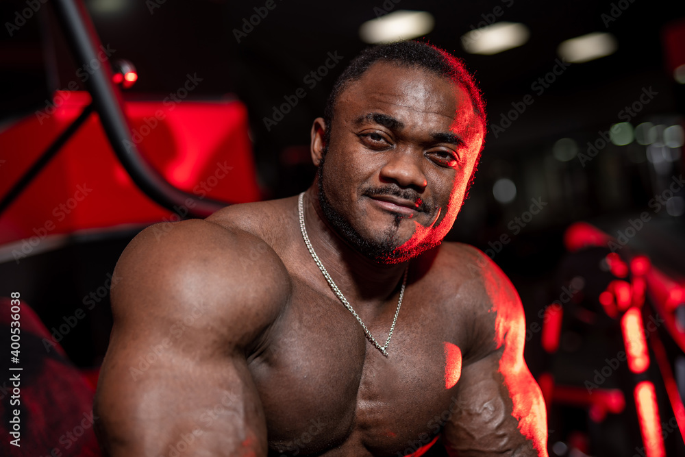 Handsome man with big muscles, posing at the camera in the gym. African ...