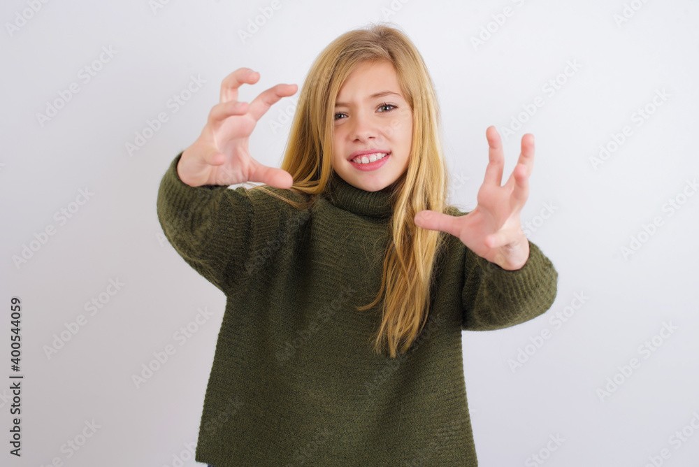 Caucasian kid girl wearing green knitted sweater against white wall ...