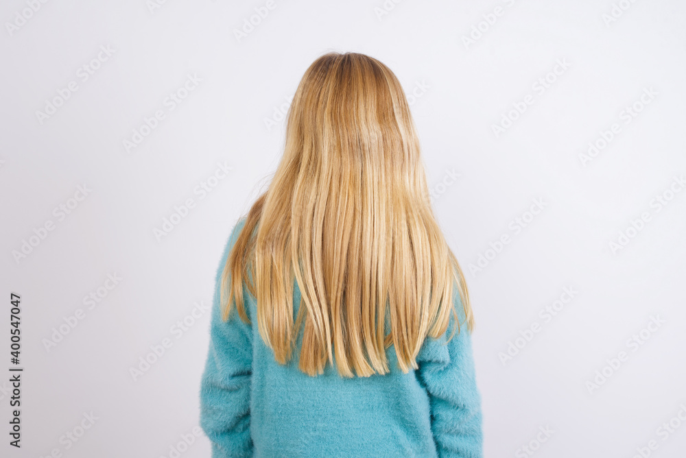 Cute Caucasian kid girl wearing blue knitted sweater against white wall ...