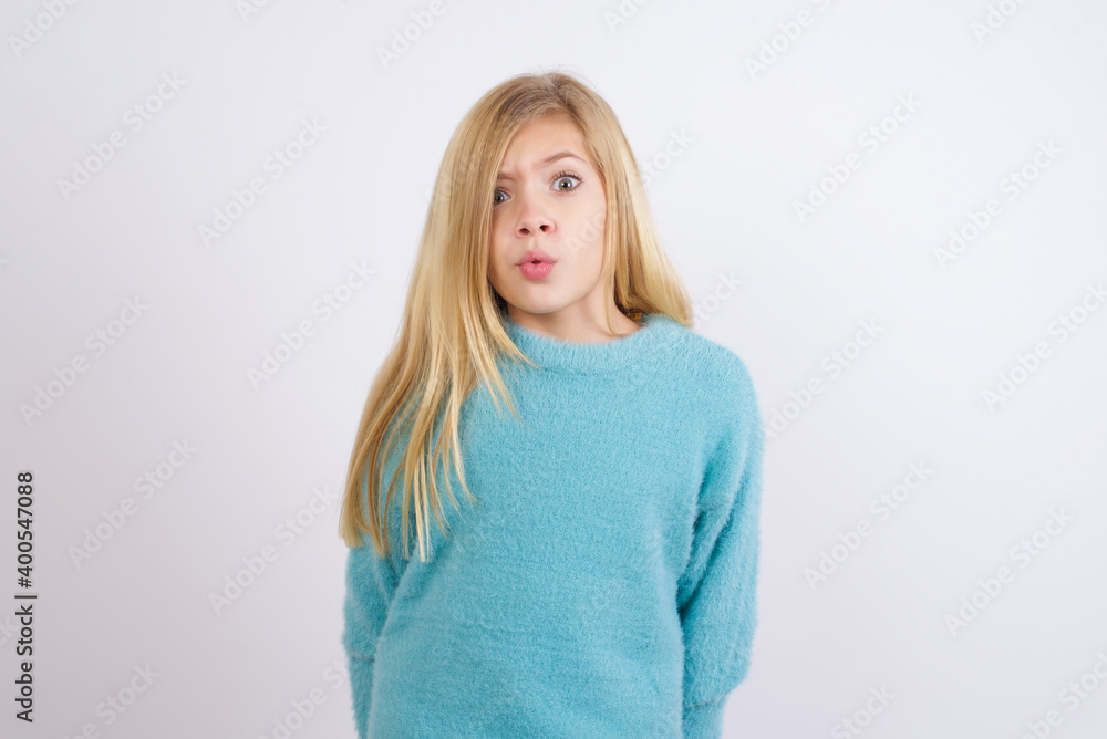 Cute Caucasian kid girl wearing blue knitted sweater against white wall ...