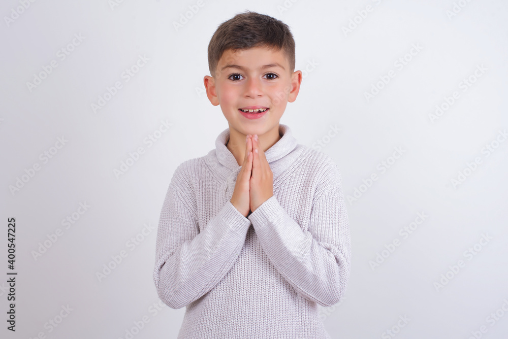 Cute Caucasian kid boy wearing knitted sweater against white wall ...