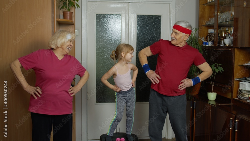 Granddaughter and mature grandparents in sportswear making sports ...
