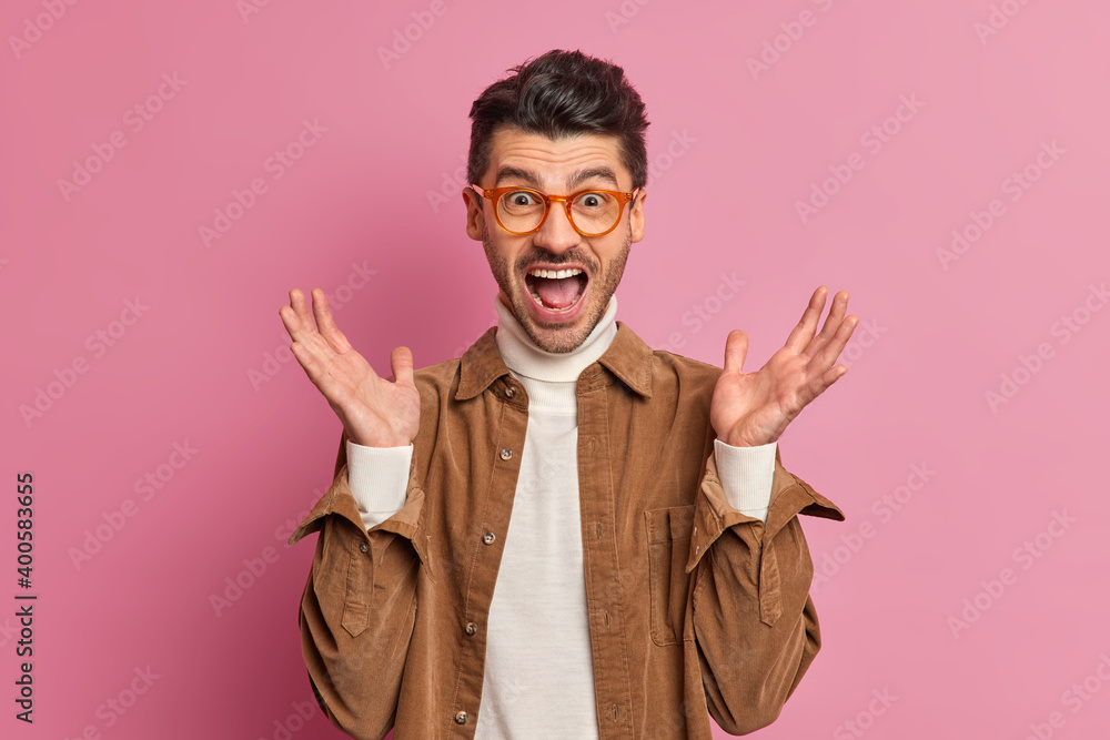 Isolated shot of emotional unshaven adult man raises palms and shouts ...