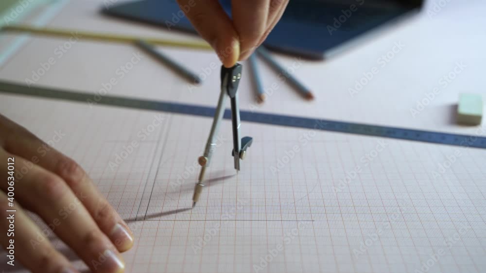 Unrecognizable drafter using compass to draw circle on graph paper ...