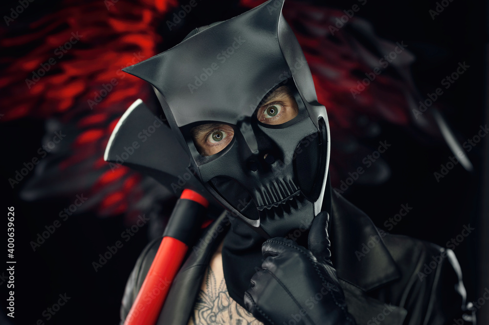 a man in a demon skull mask in a leather cloak with an axe on a ...