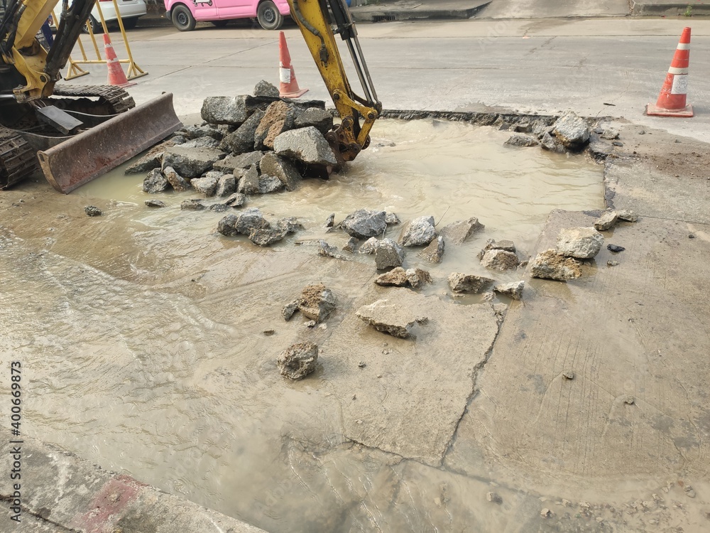 Excavators dig holes to destroy concrete roads to repair damaged water ...