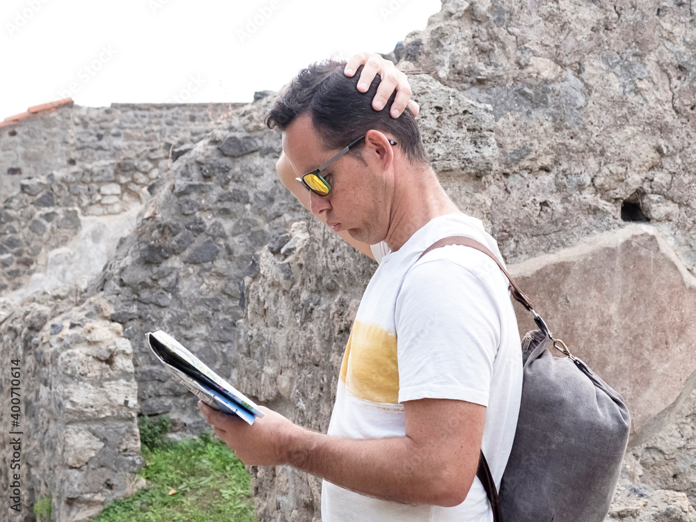 Confused traveler backpacker man exploring ancient ruins while checking ...