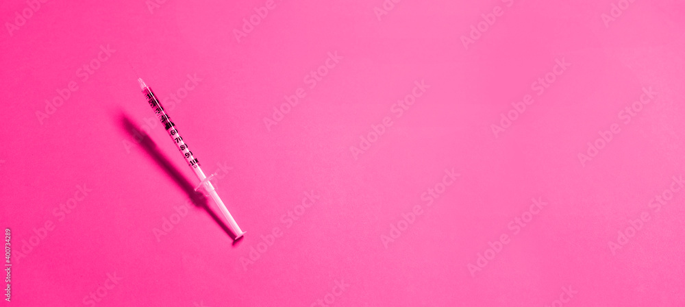Medical syringe with a sharp needle in the air over a minimalist pink ...