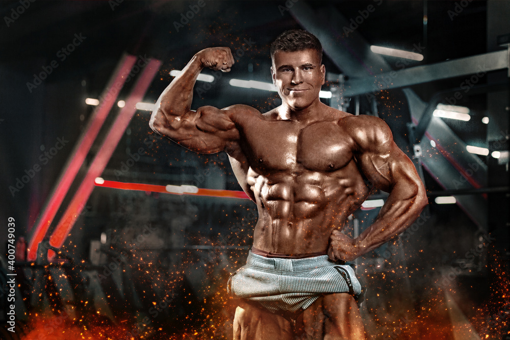 Bodybuilder athlete man pumping up muscles in the gym. Brutal strong ...