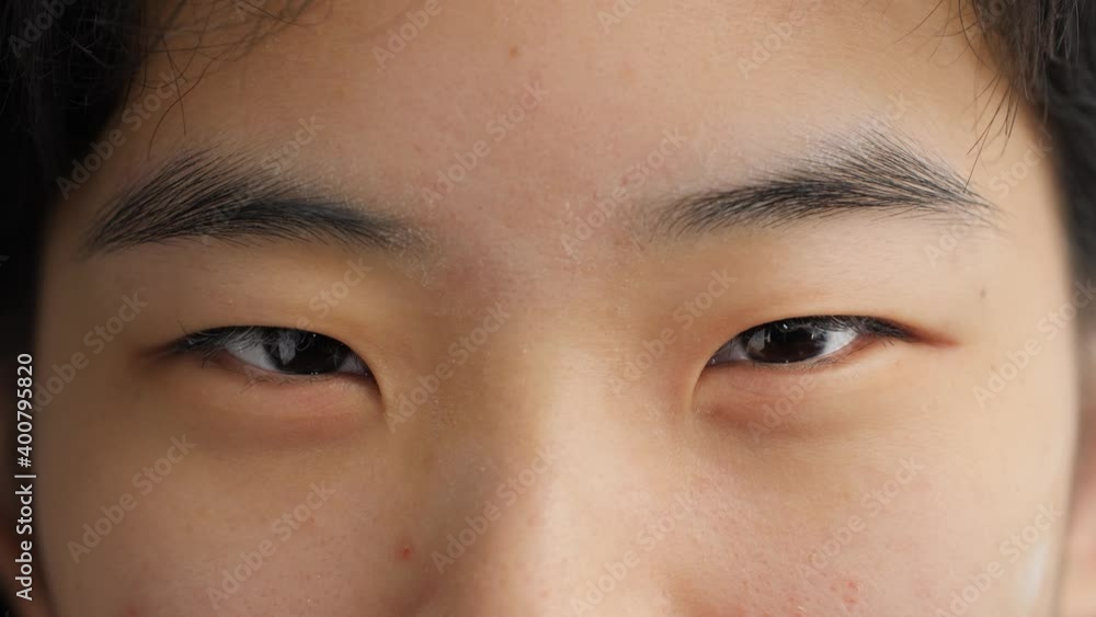 Face of cute and happy young Asian woman looking and winking at camera ...