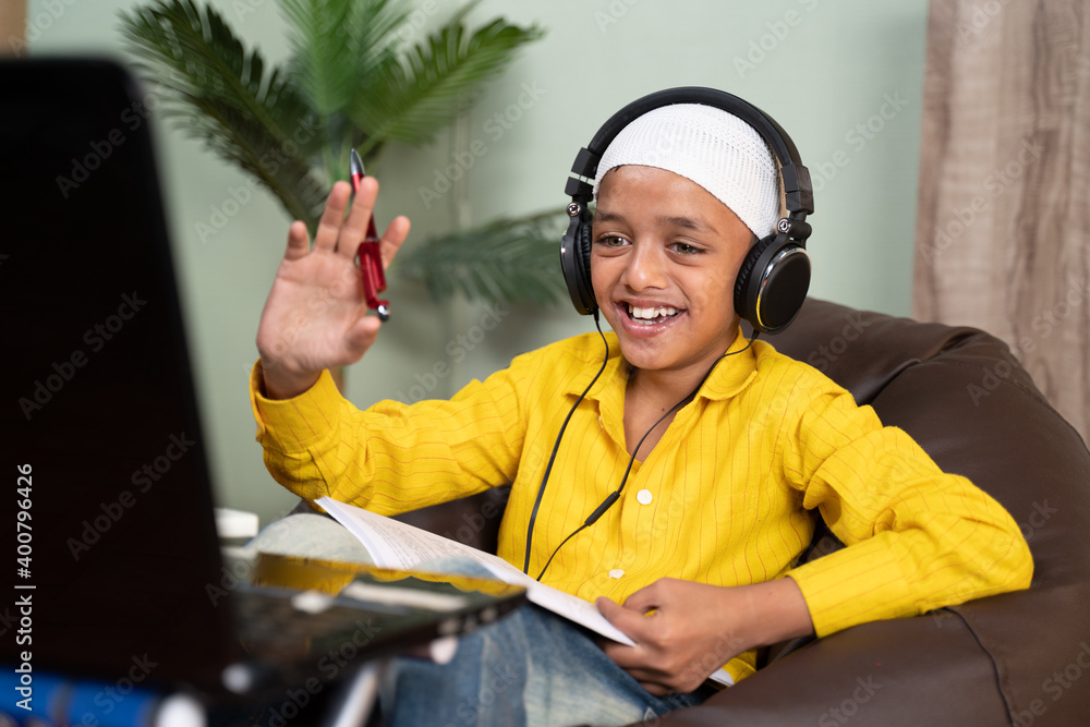 Muslim kid busy on online class by making video call on laptop ...