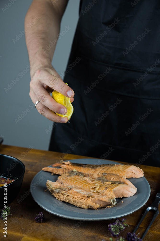 Chief cook squeezes lemon on carved fish baked in salt crust. Seafood ...
