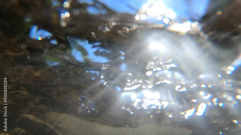 Flowing water, skylight of sun through water, stones lying at bottom ...