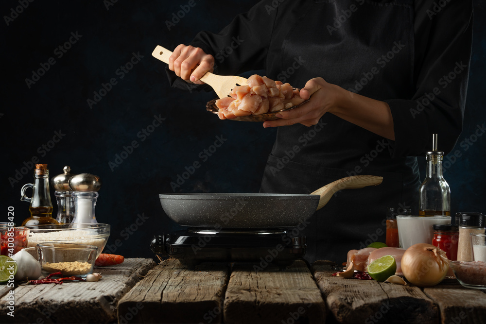 Professional chef pours chopped chicken fillet into pan. Backstage of ...