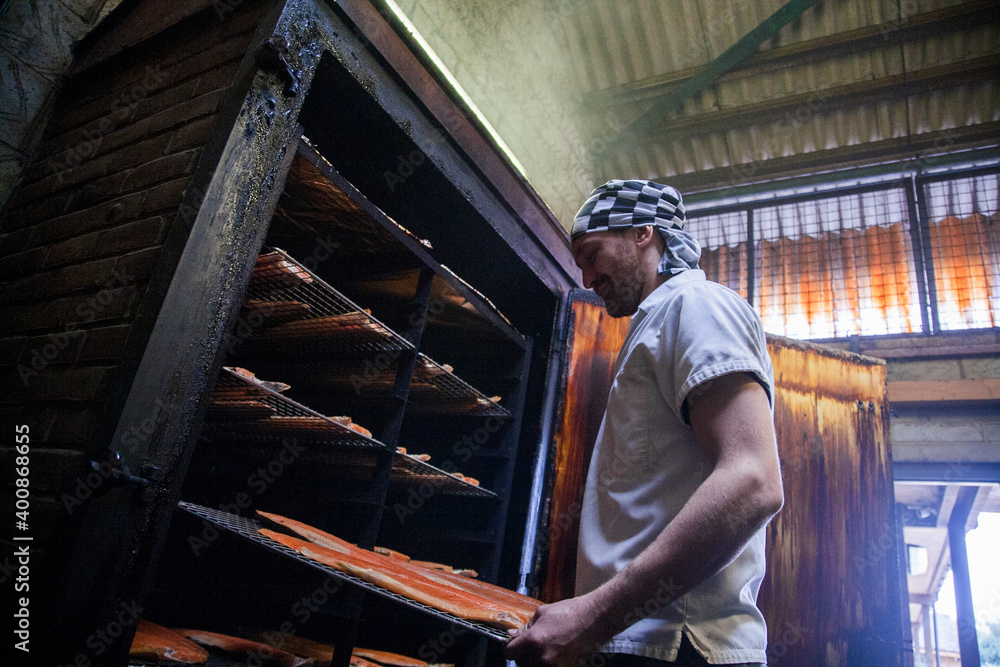 Manual worker inserting fish tray in smokehouse at food factory Stock ...
