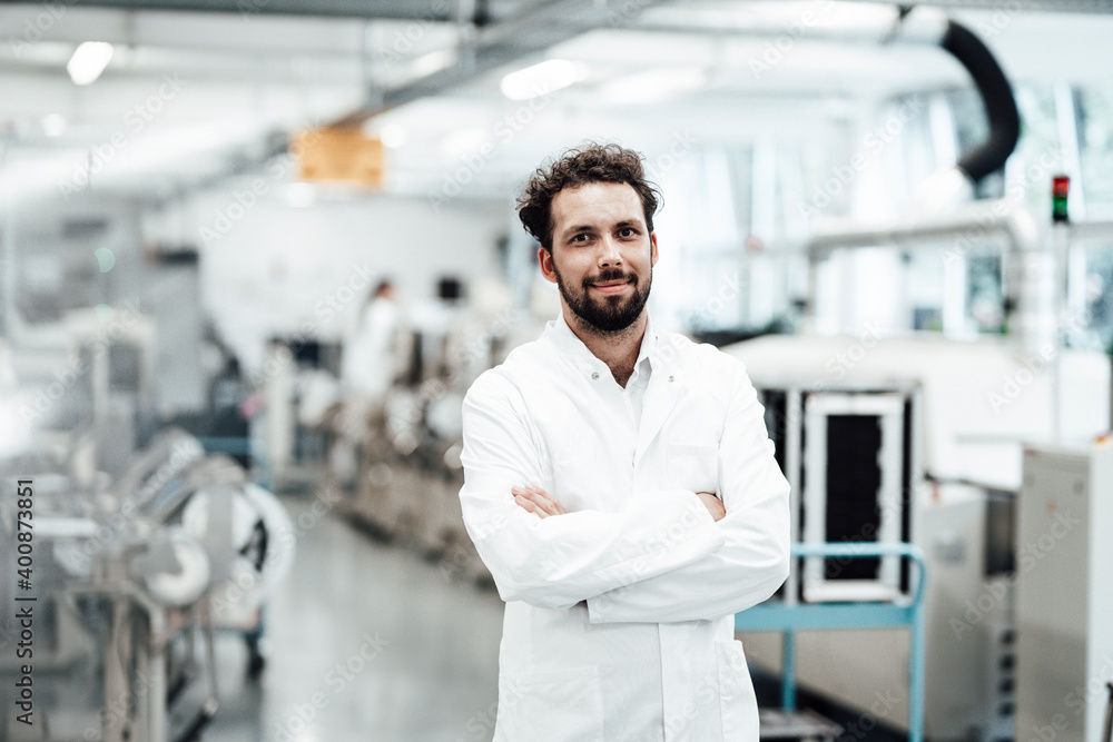Confident male scientist in white lab coat while standing with arms ...