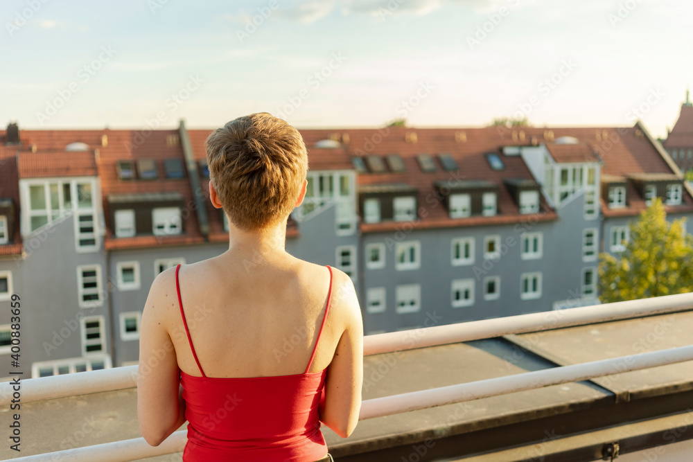 Woman with short hair looking at building while standing in balcony ...