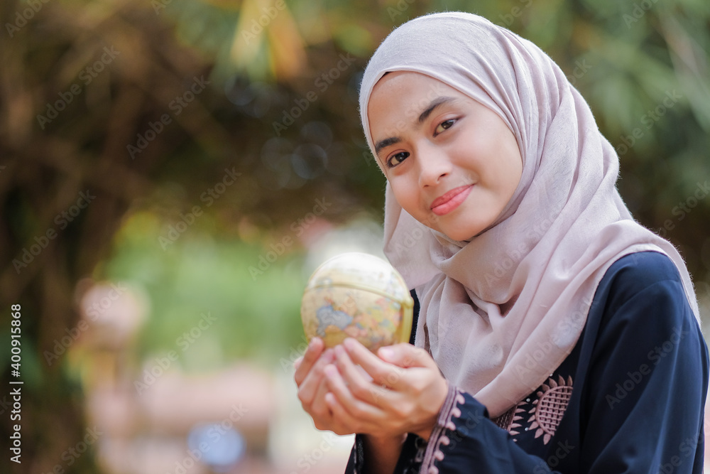 Young Malay muslim student girl in hijab black clothes hold in hands ...