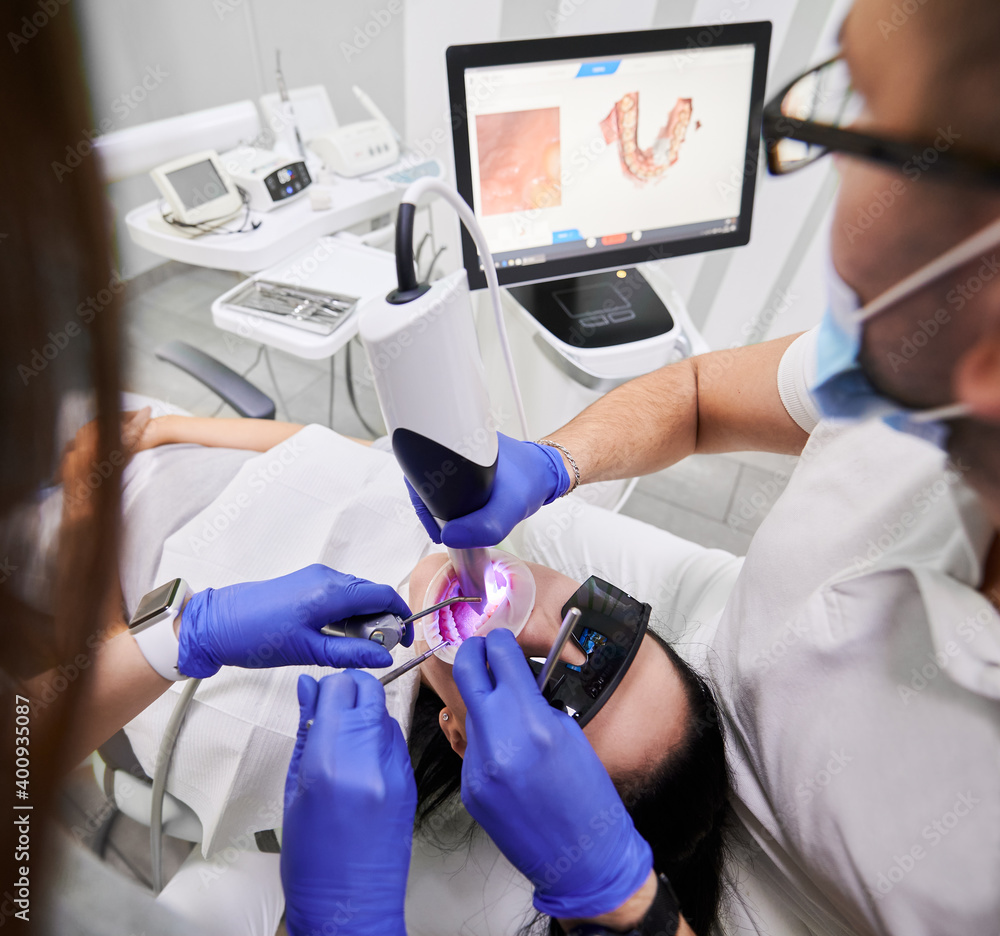 Dentist and assistant using intraoral scanner while examining patient ...