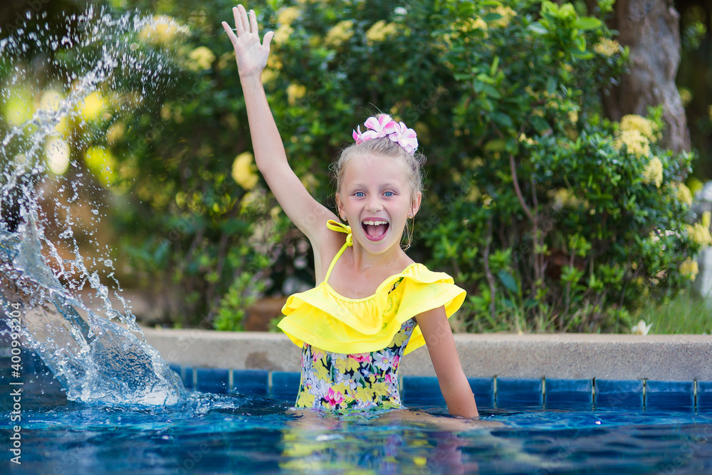 Little girl playing and spraying water in swimming pool outdoors at ...
