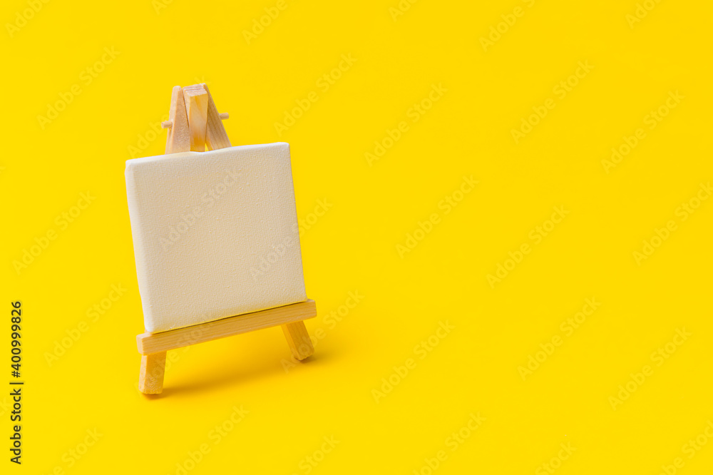 Wooden molbert with a paper attached to it isolated on a yellow ...