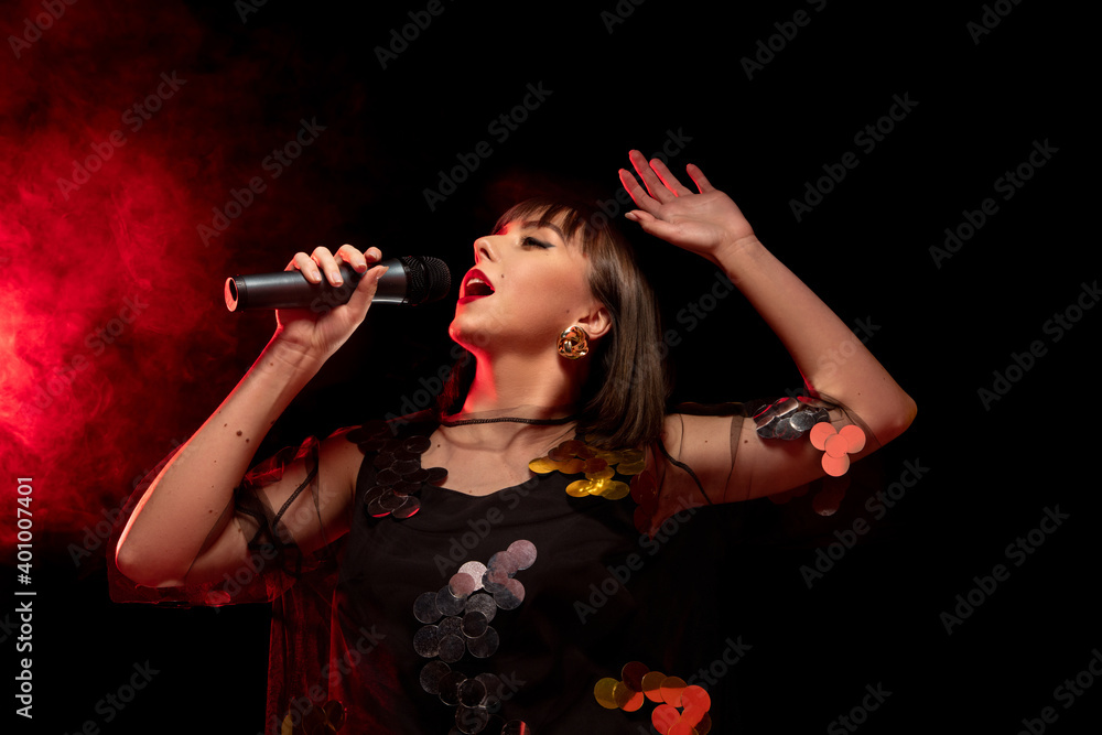 Performance. Caucasian female singer portrait isolated on dark studio ...