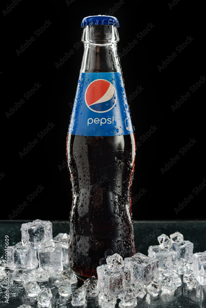 Misted glass bottle of Pepsi Cola on a black background with ice cubes ...