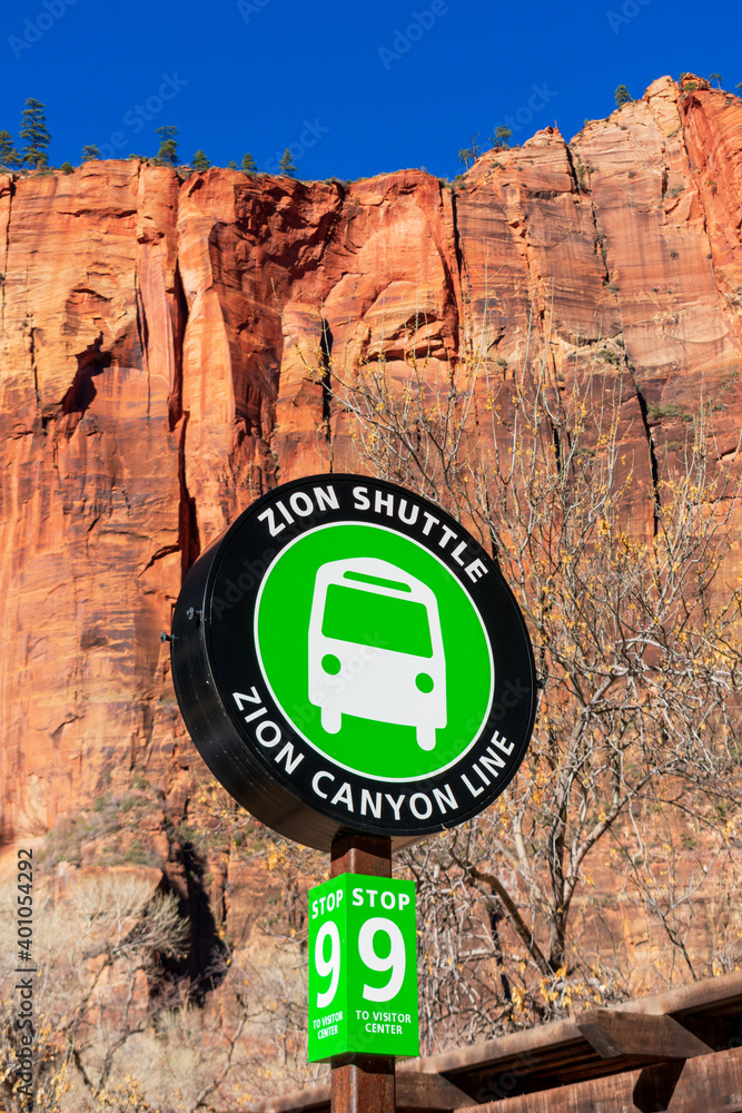 Zion shuttle sign at Zion Canyon Line bus stop with steep red cliffs ...