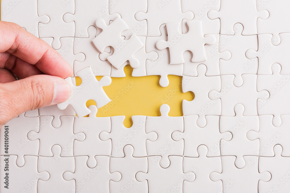 Top view flat lay of hand-holding last piece white paper jigsaw puzzle ...