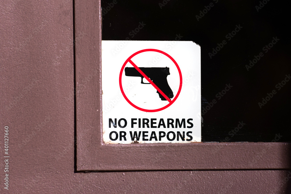 No firearms or weapons sign on the glass entrance door to the business ...