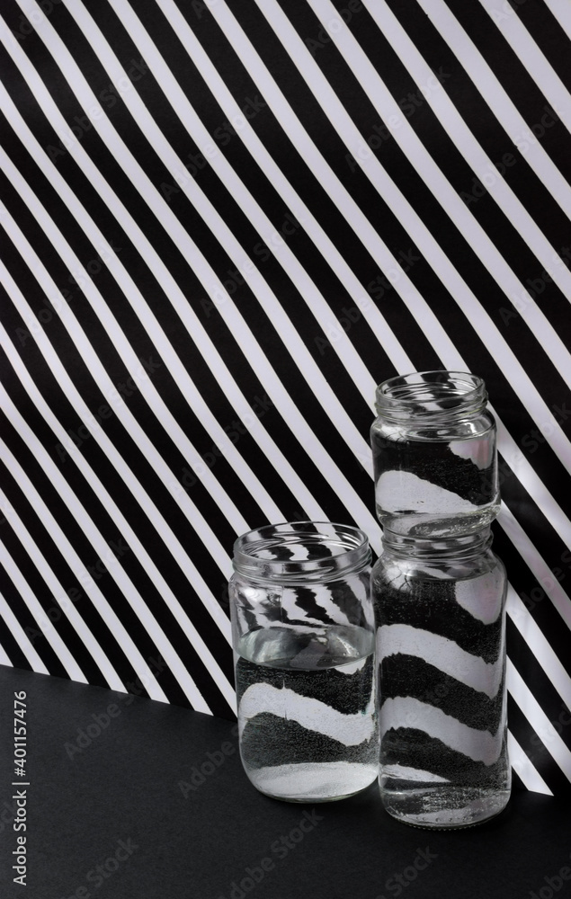 Three glass jars of different sizes with water. Background of white and ...