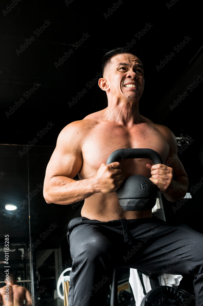 A strong athletic shirtless asian man does some goblet squats with a ...