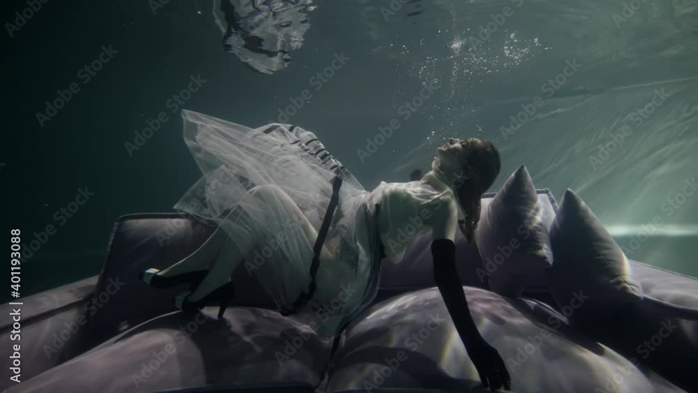 A female model in a long dress and heels poses beautifully on a gray ...