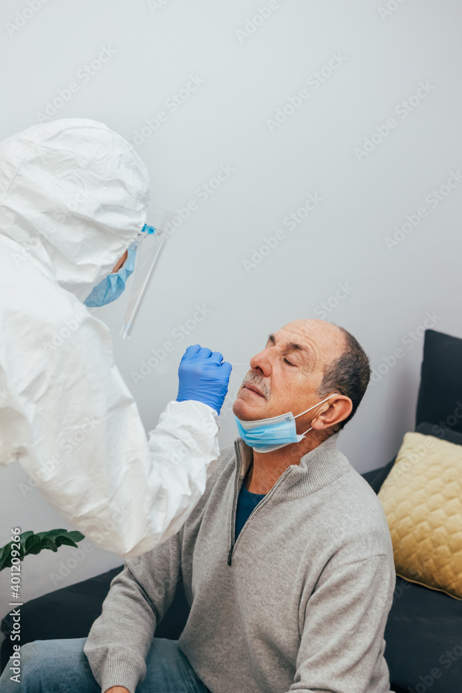 Health Professional in PPE suit and face shield inserting a nasal swab ...
