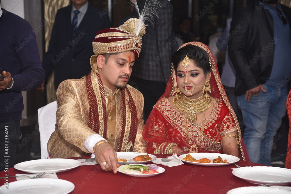 Bride groom having food during wedding ceremony. Both are wearing ...