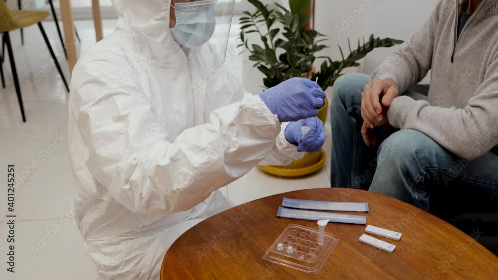 Protected health professional introducing the nasal swab to the buffer ...