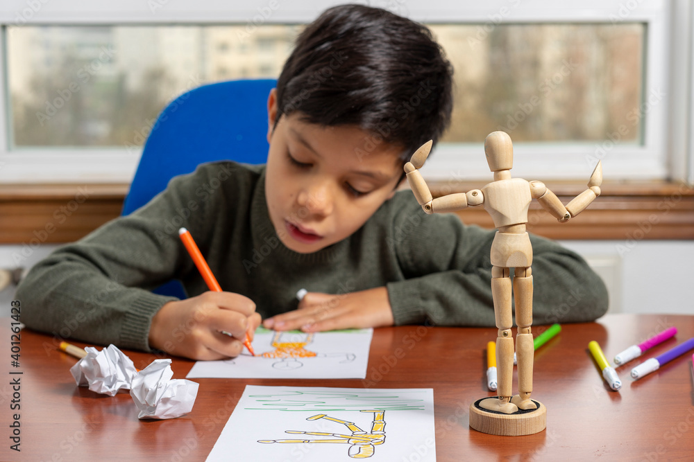 Child painting with markers his drawings that he made of a human figure ...
