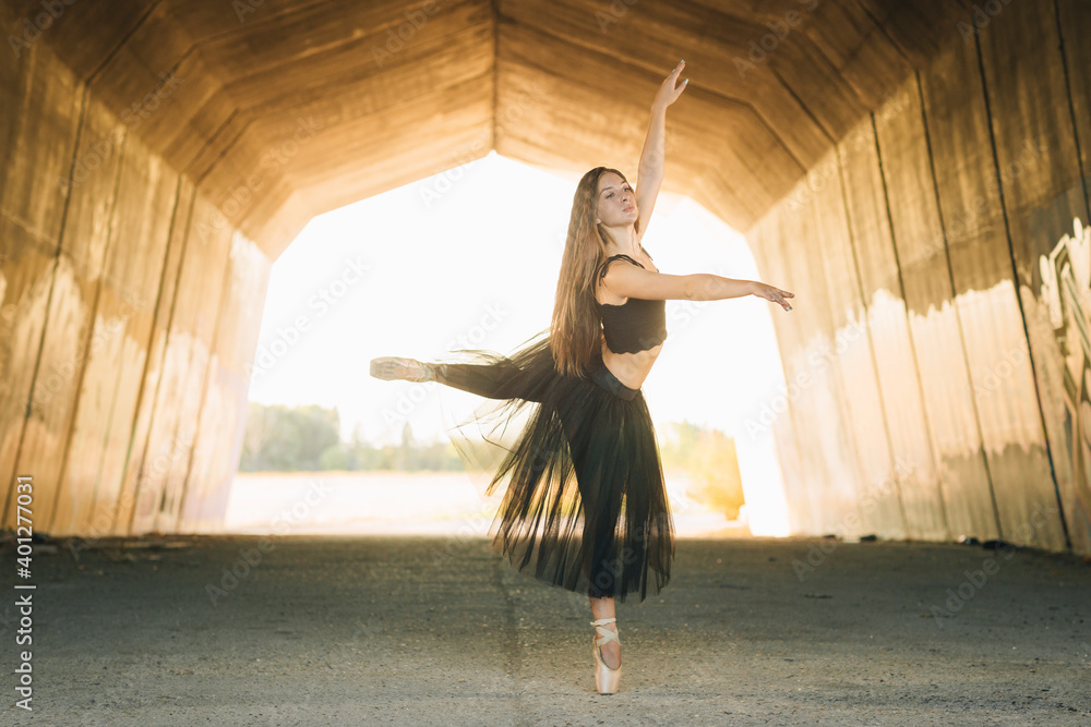 Foto de Elegant ballerina in black tutu and pointe shoes balancing on ...