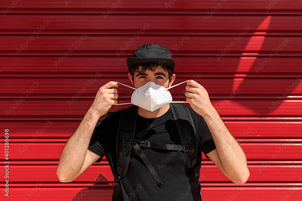Unrecognizable trendy guy in black apparel putting on respiratory mask ...