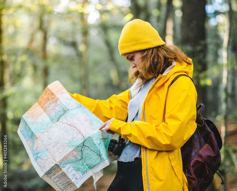 Side view of female explorer in yellow raincoat and with backpack ...