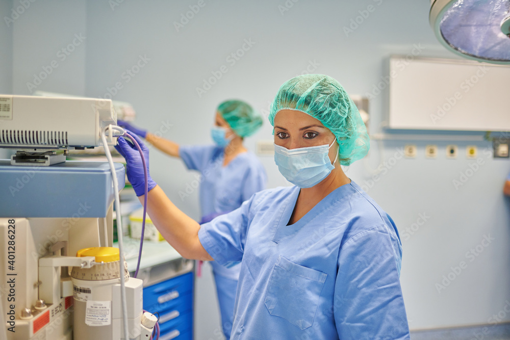 Side view of female medic in uniform touching monitor of medical ...